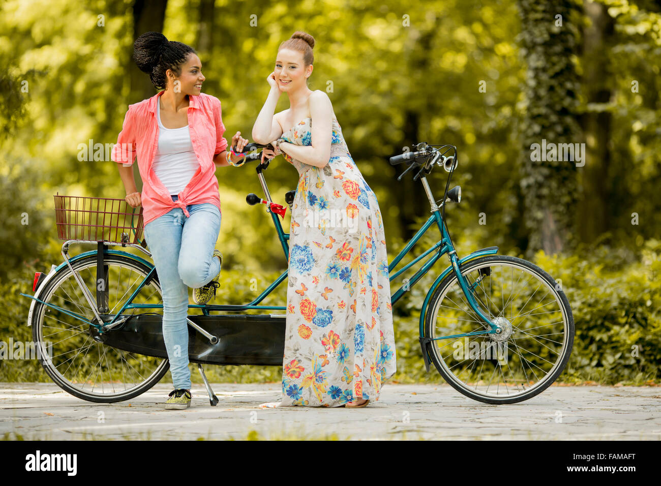 Young women posing by the bicycle Stock Photo - Alamy