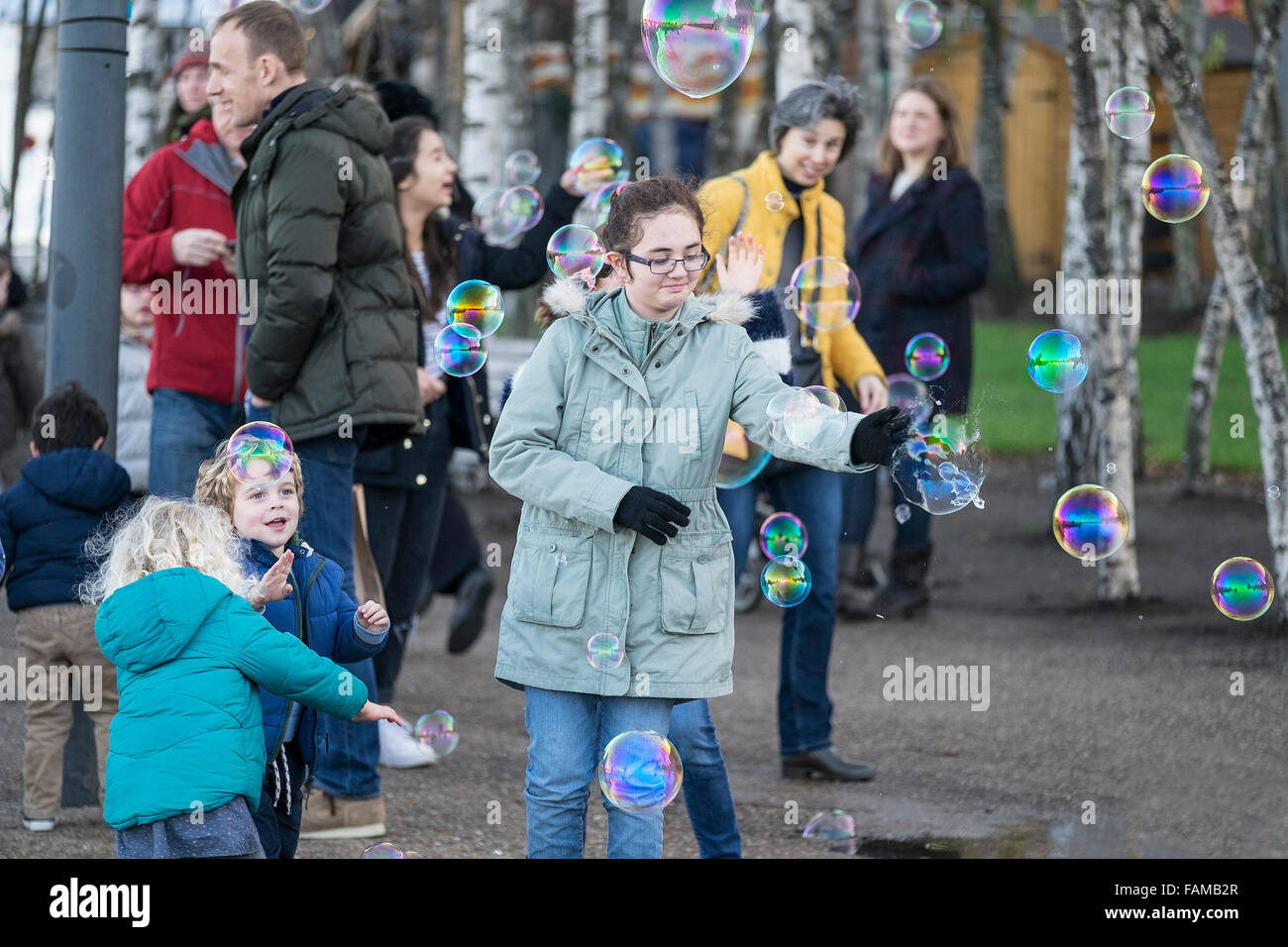 Excited children chasing bubbles created by a street entertainer on the ...