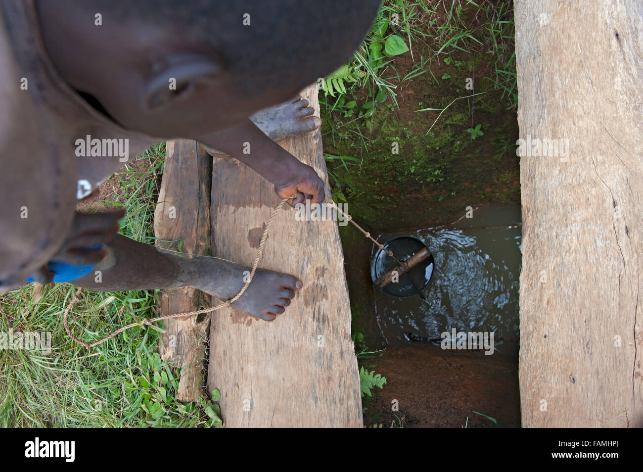 Child drawing water up from a deep well with bucket and rope. Kenya ...