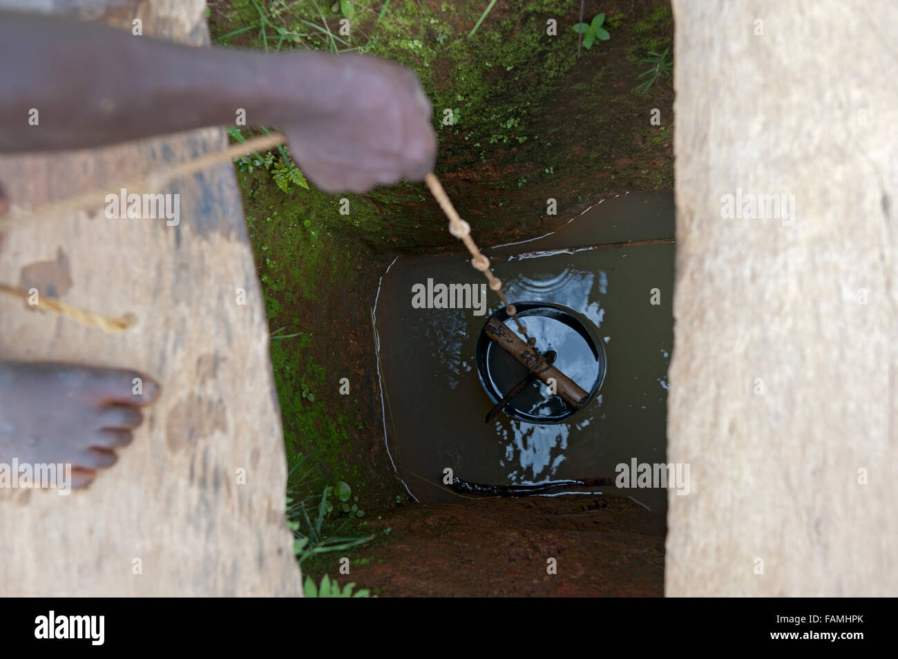 Child drawing water up from a deep well with bucket and rope. Kenya ...