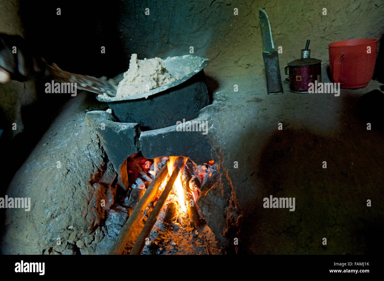 Cooking meal over an open fire in a small basic kitchen unit, Kenya ...