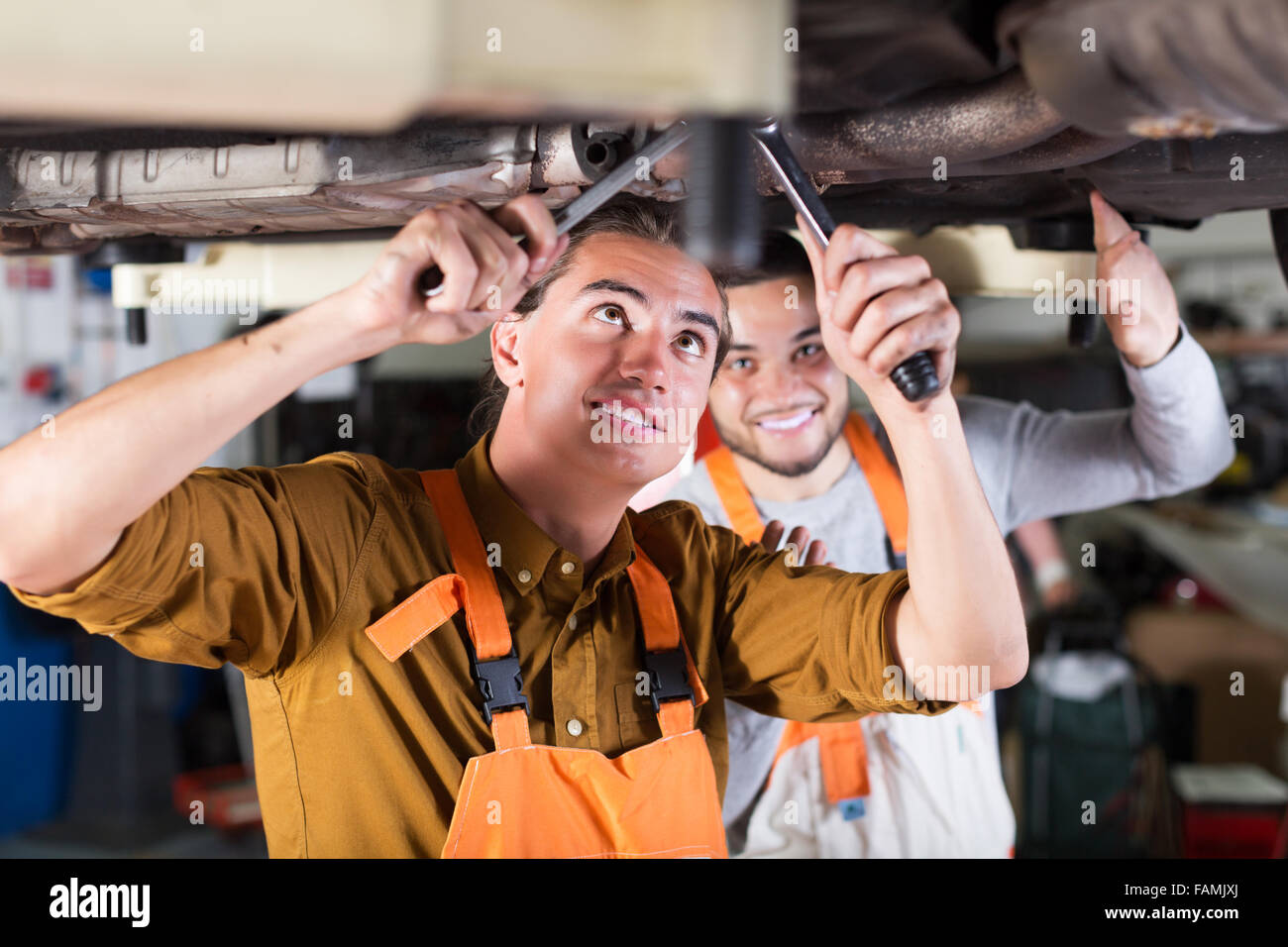 Professional smiling serviceman repairing car of client Stock Photo - Alamy