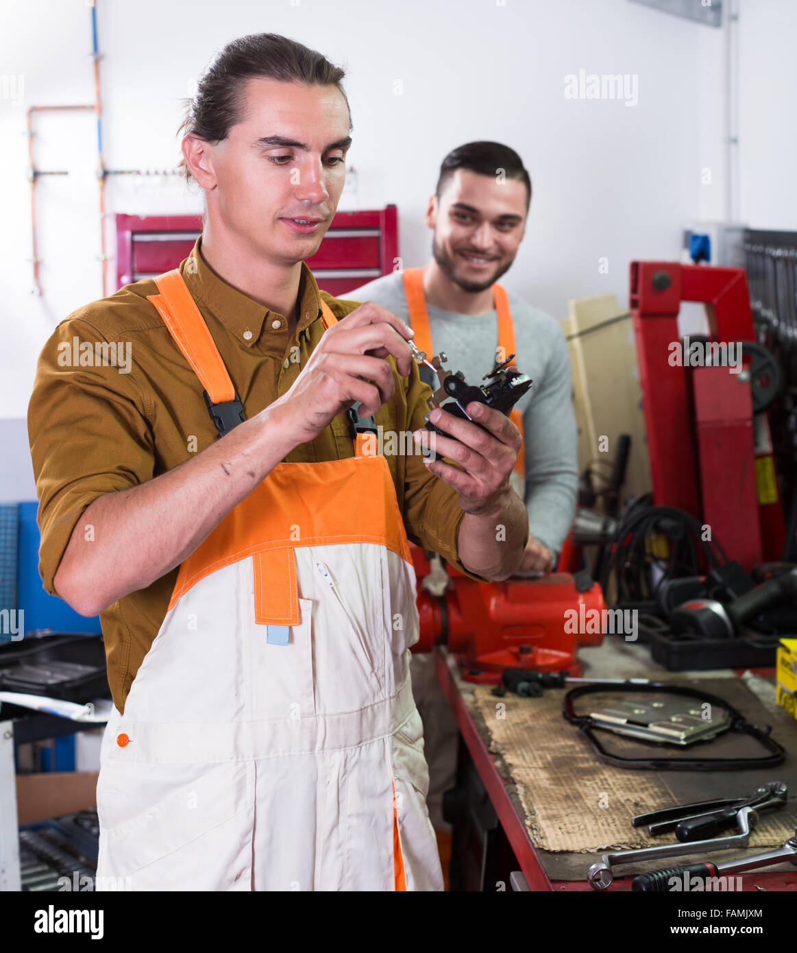 Two workmen toiling in locksmiths workshop and smiling Stock Photo - Alamy