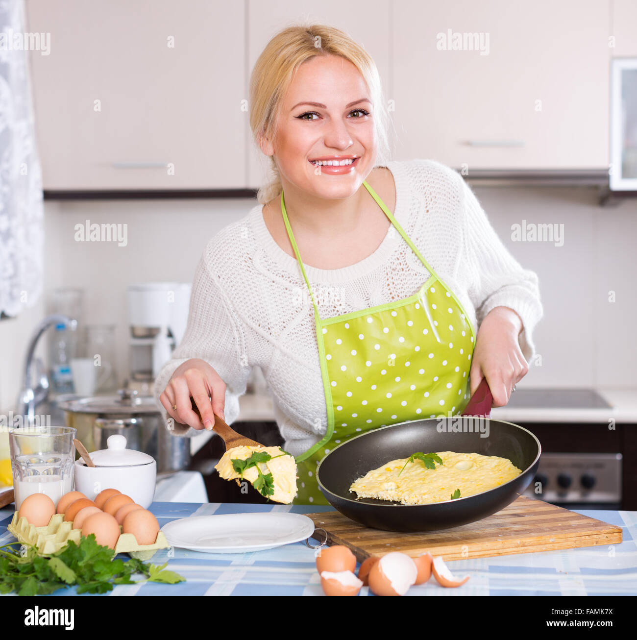 Smiling housewife making omlet in kitchen Stock Photo - Alamy