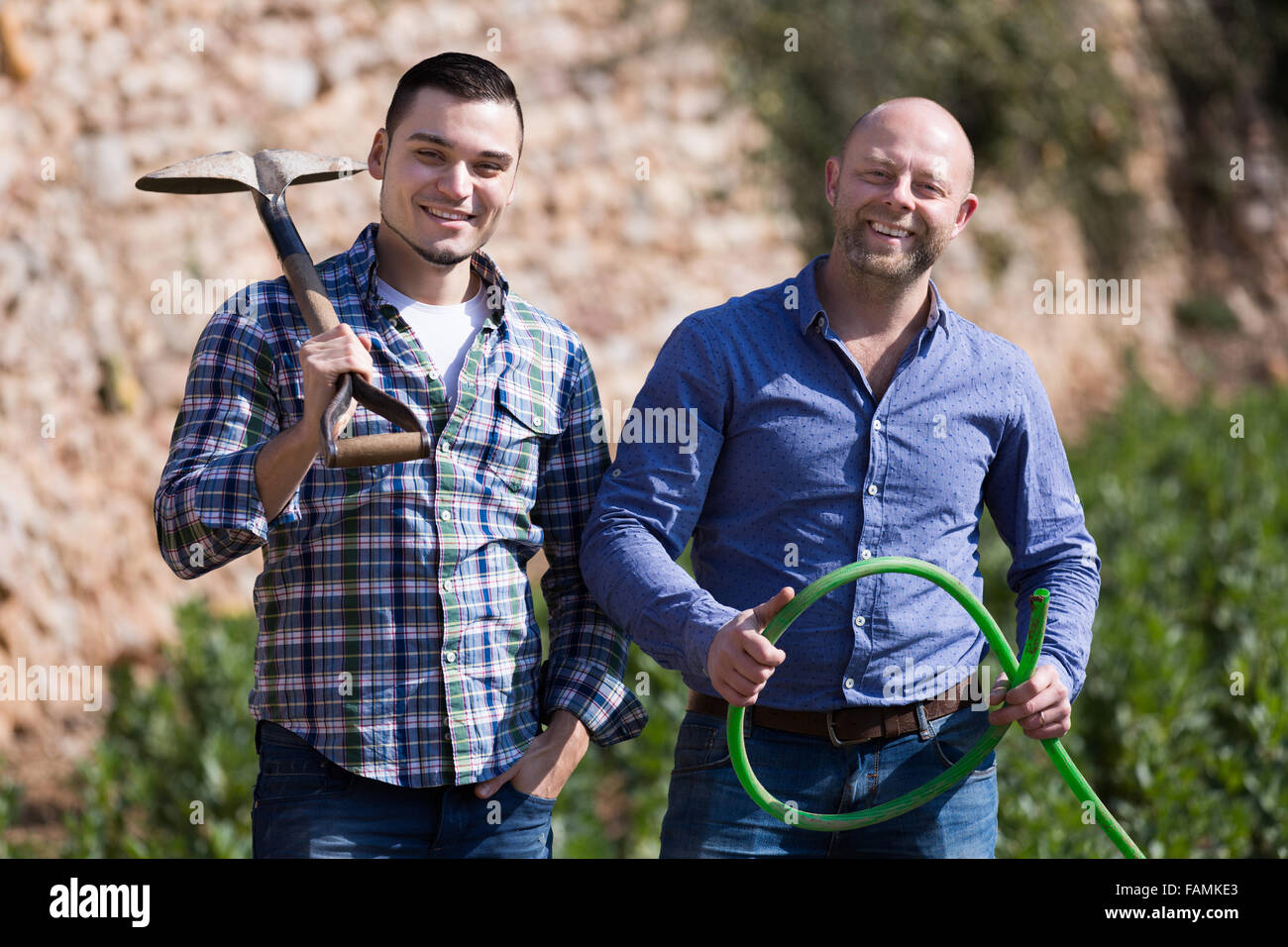 Two male farmers standing with spades at plantation Stock Photo - Alamy