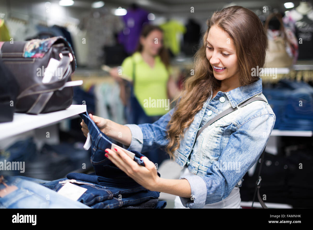Smiling girl shopper choosing new jeans at store Stock Photo - Alamy