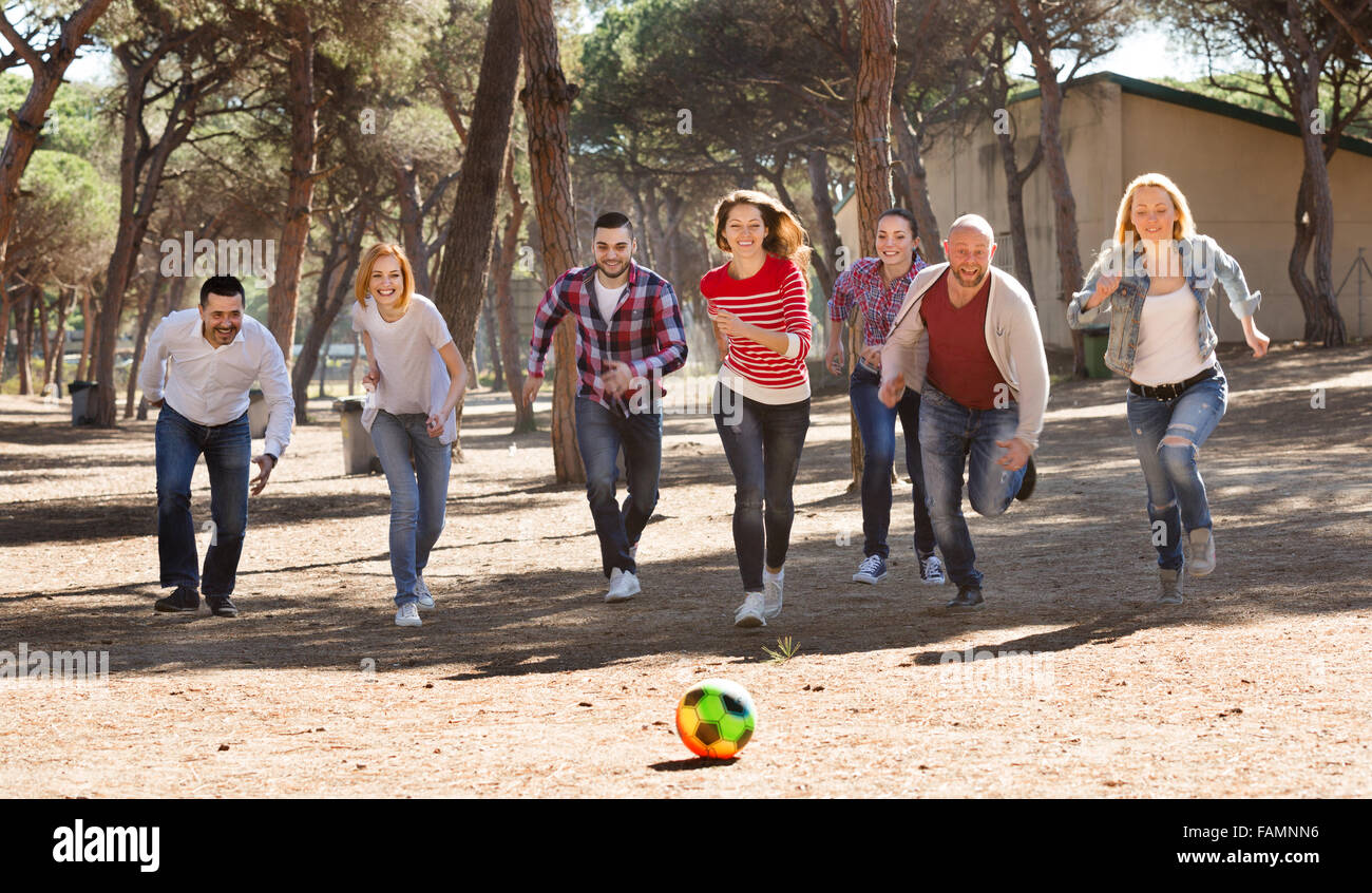 Several positive friends running with a ball and laughing Stock Photo ...