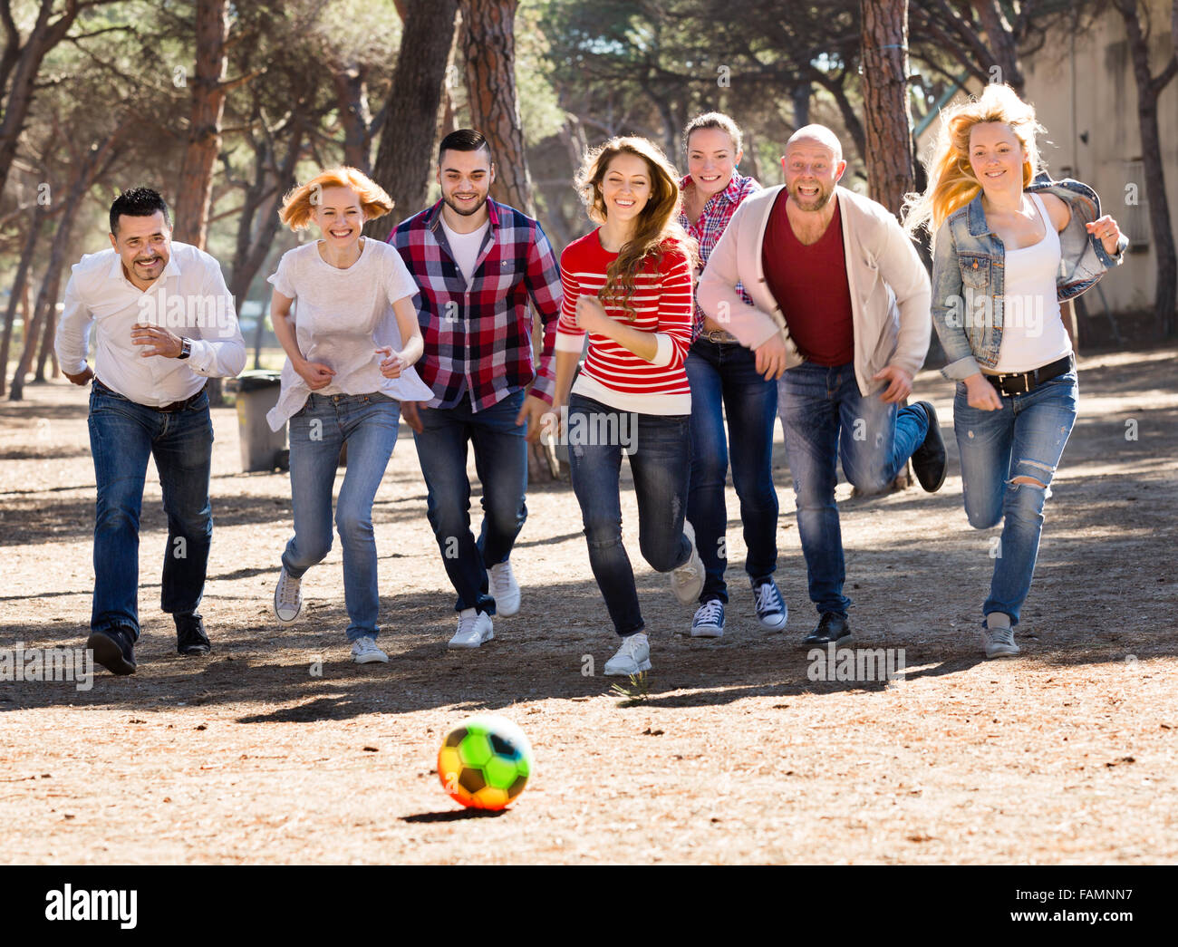 Several happy friends running with ball and laughing Stock Photo - Alamy