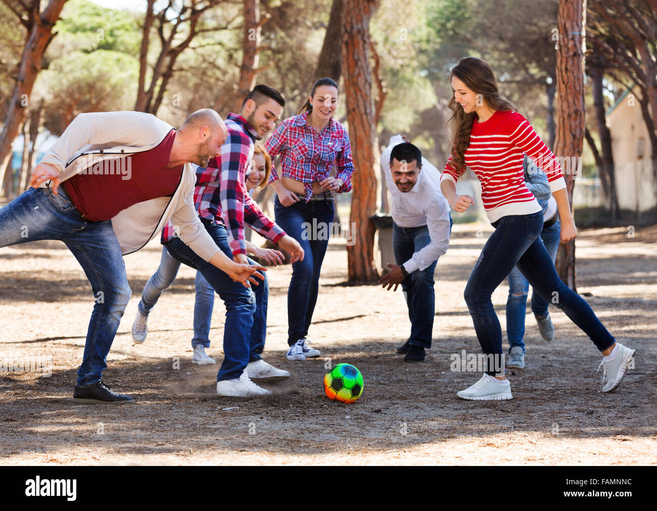 Several cheerful friends running with ball and laughing Stock Photo - Alamy