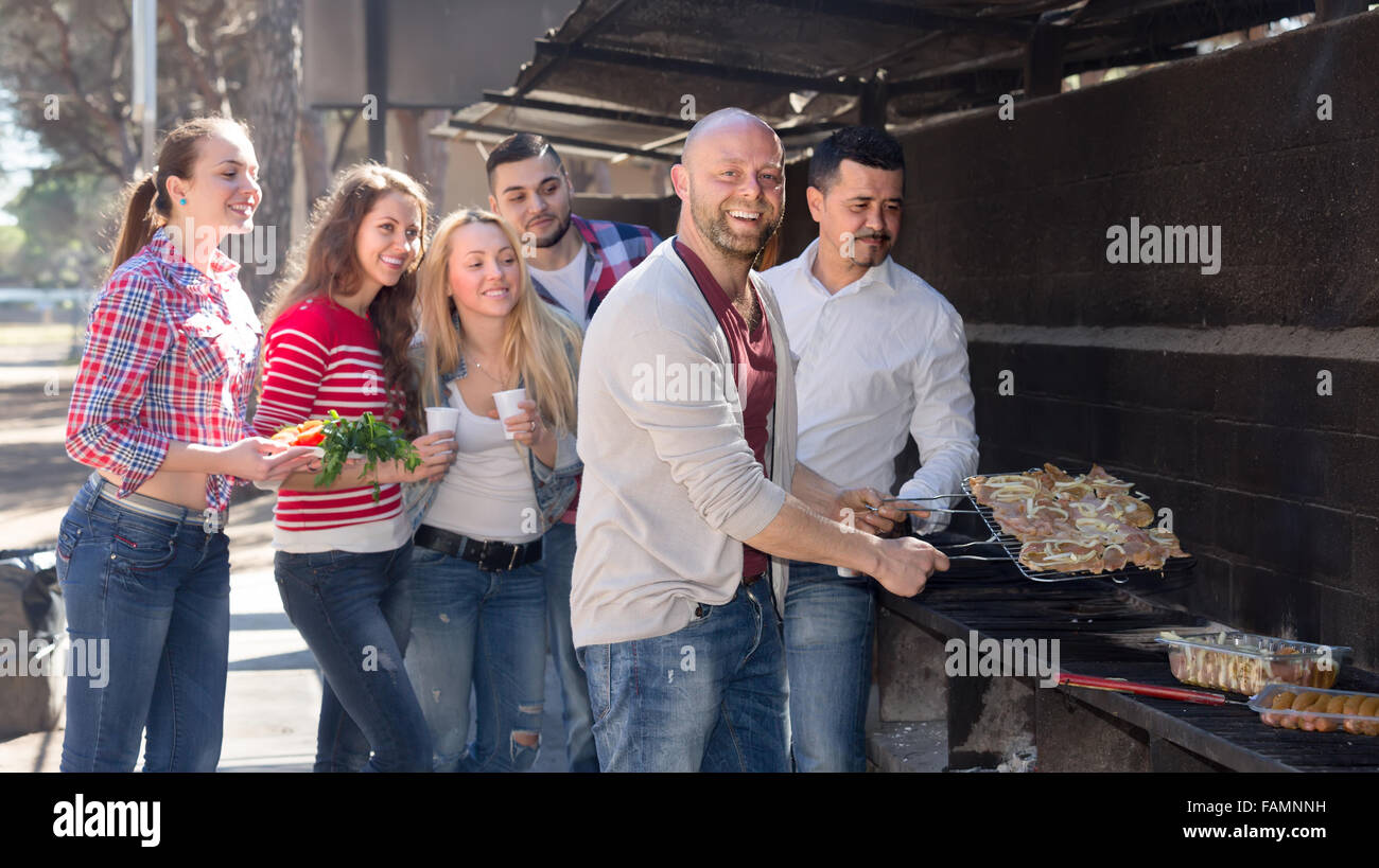 Positive smiling colleagues making grill at corporate party outdoor ...