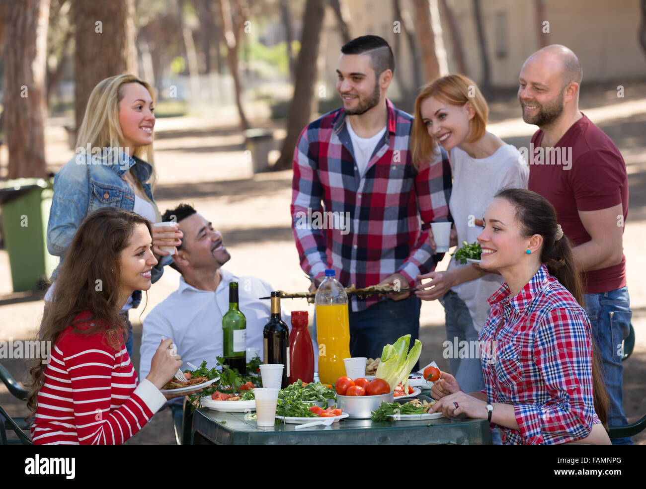Group of happy friends making grill at summer corporate party outdoors ...