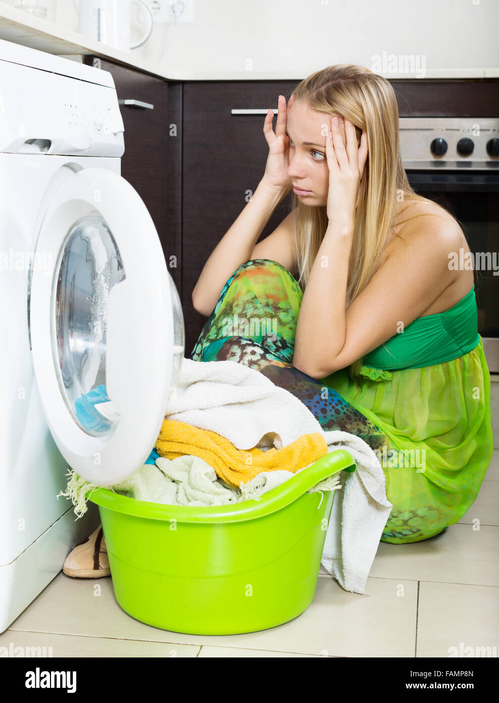 Unhappy young blonde girl using washing machine at home Stock Photo - Alamy