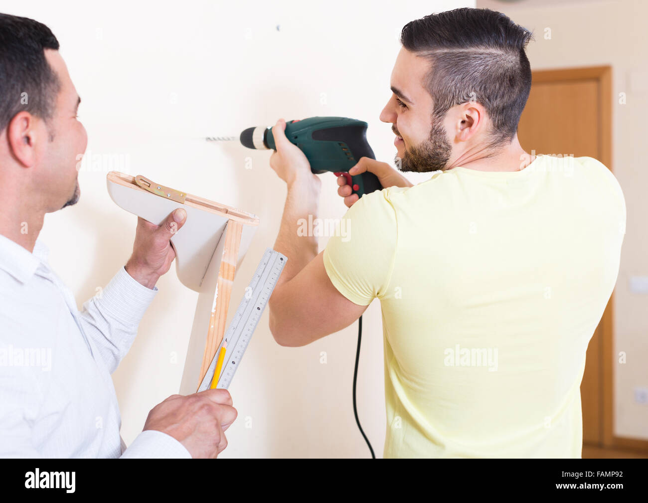 Two smiling male adults with drill and level indoor Stock Photo - Alamy