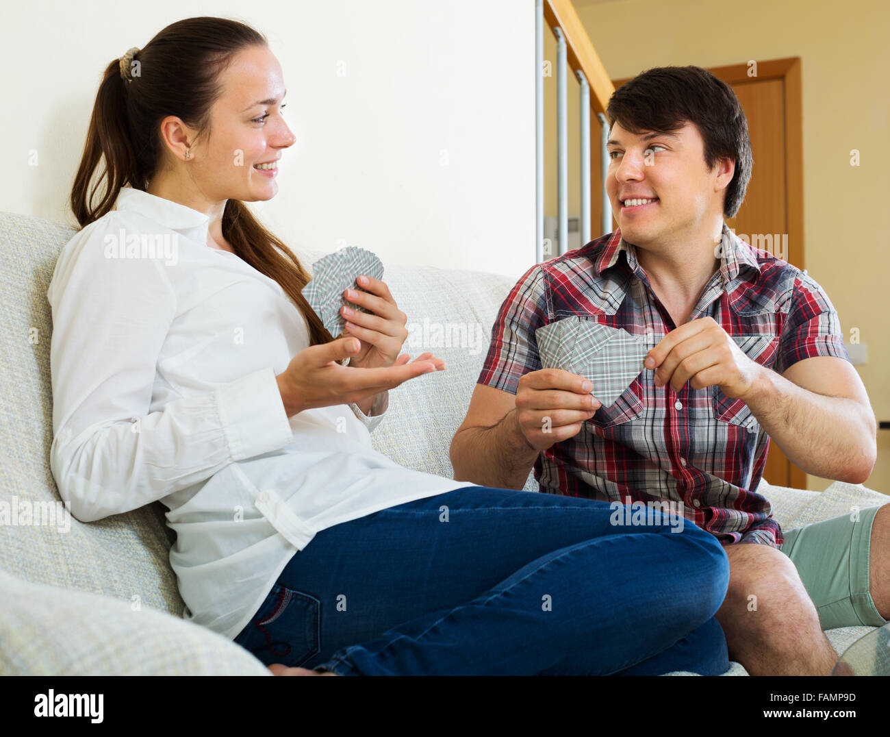 Young smiling couple playing cards and talking sitting on sofa Stock ...