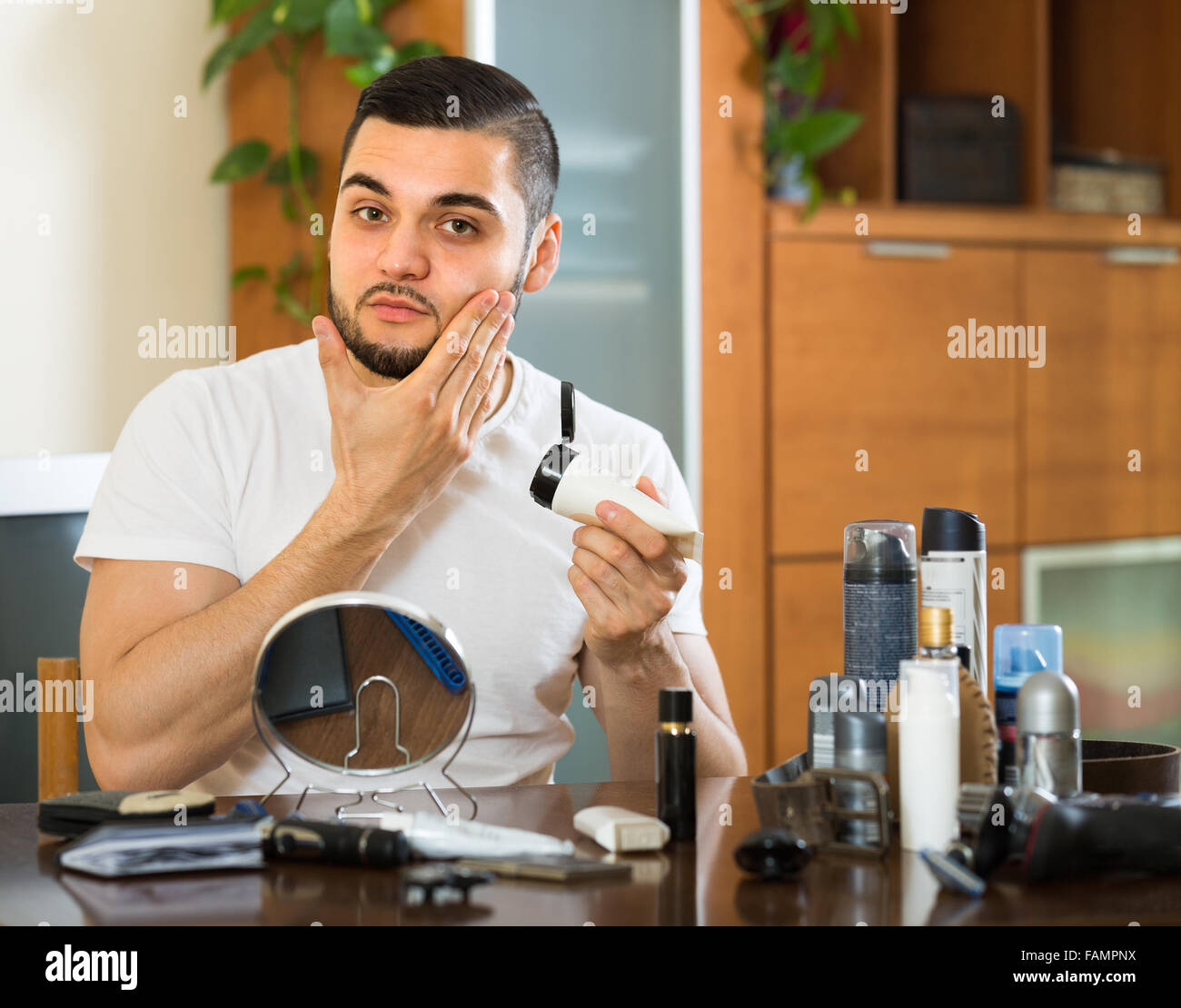 Handsome guy putting cream on face for keeping his skin in good shape Stock Photo - Alamy