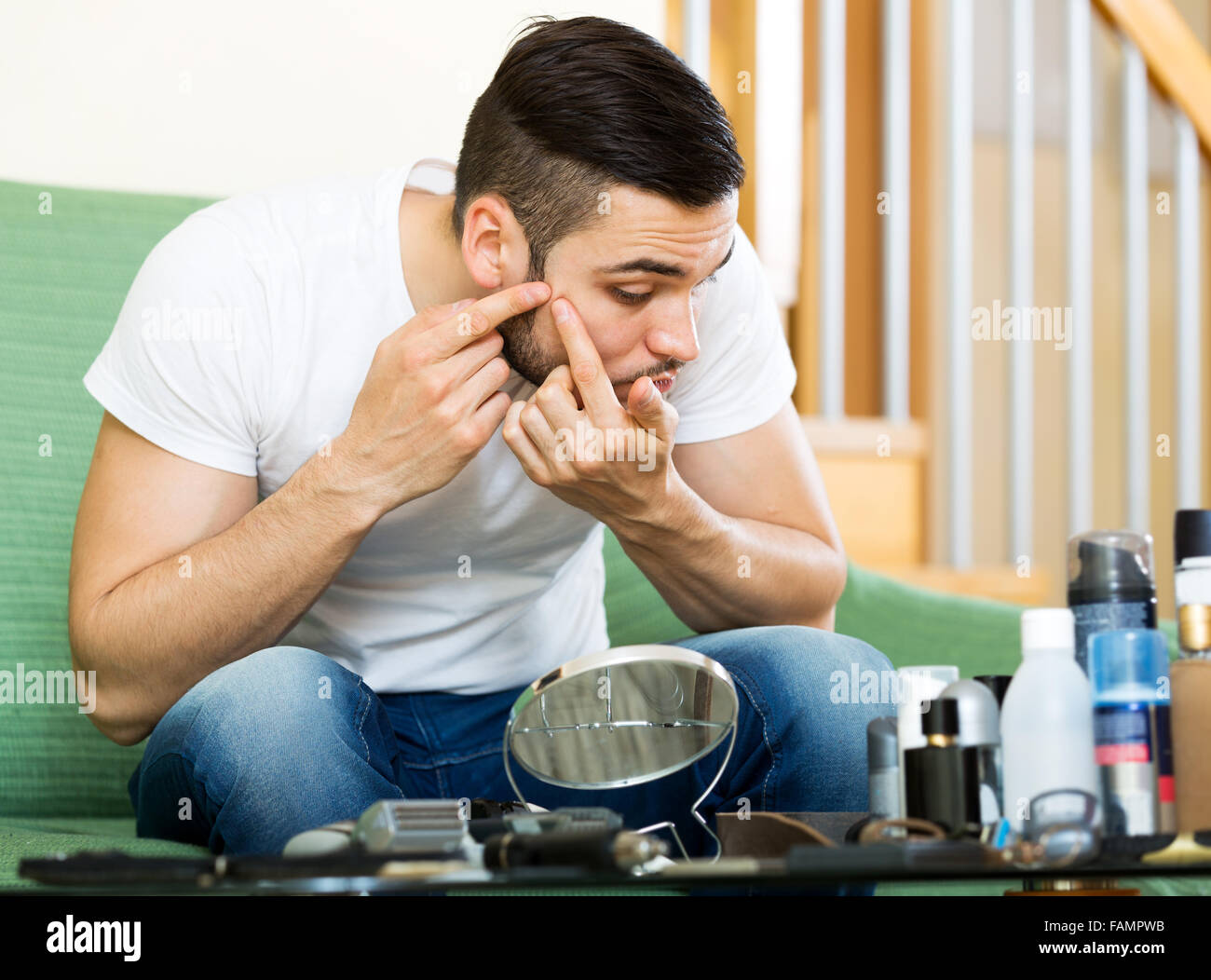 Young handsome man squeezing spot with fingers Stock Photo - Alamy