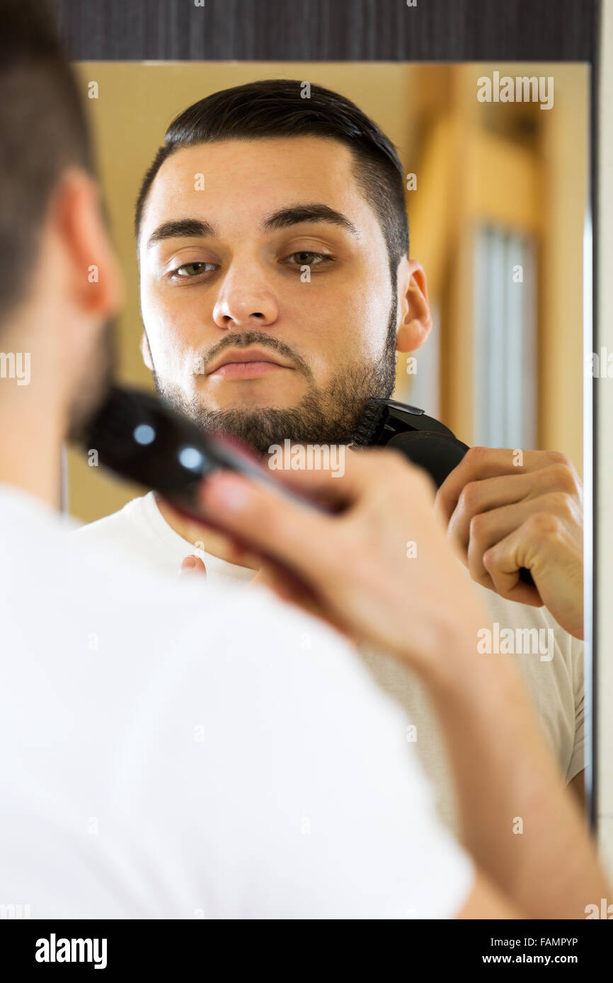 Happy young guy shaving by electric shaver at home Stock Photo - Alamy