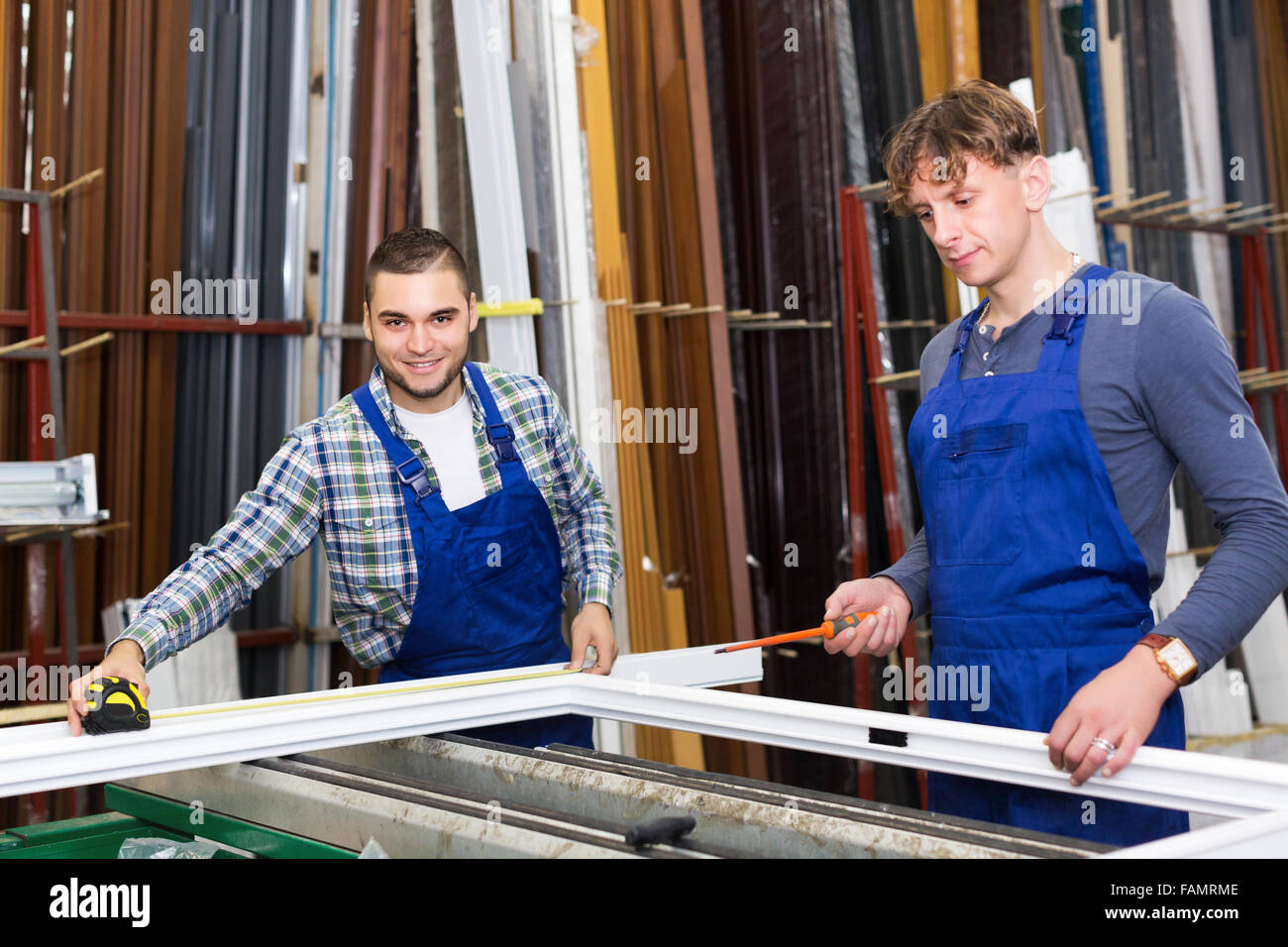 Two careful workmen inspecting windows with shutter at workshop indoor ...