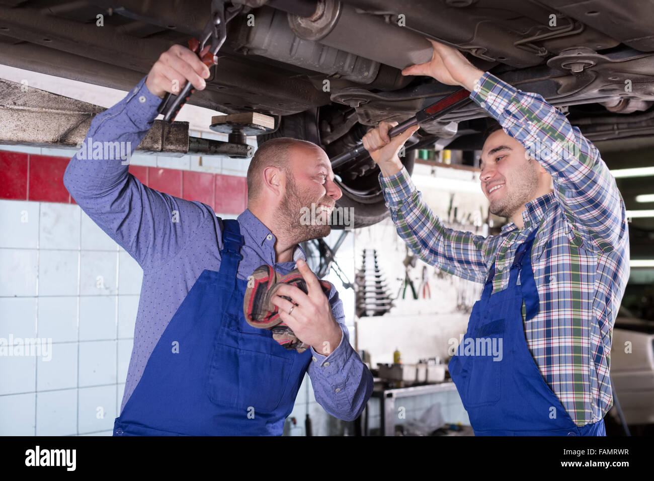 Two smiling american people fixing car tire leak Stock Photo - Alamy