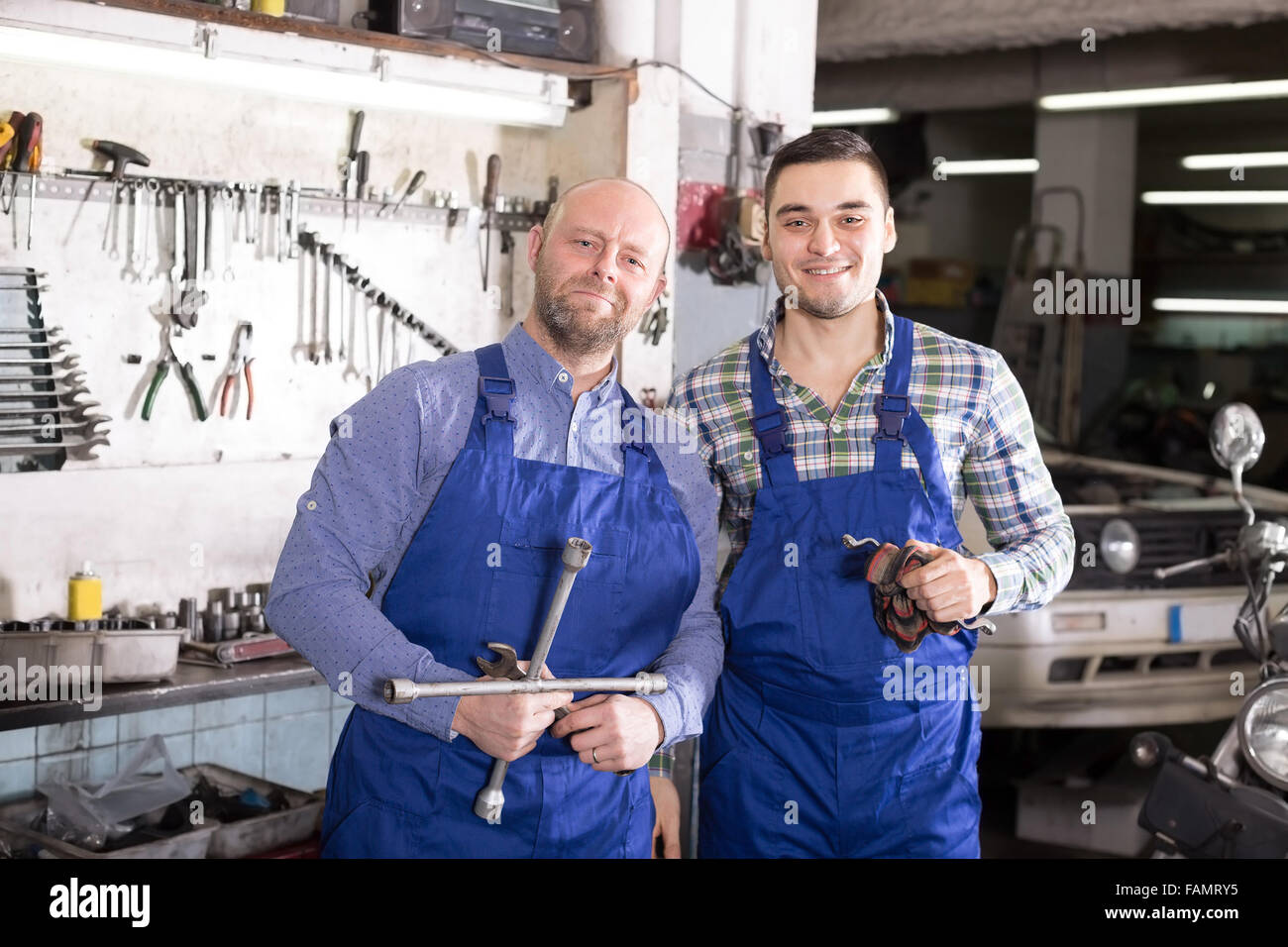 Smiling men in coveralls working at auto repair shop Stock Photo - Alamy
