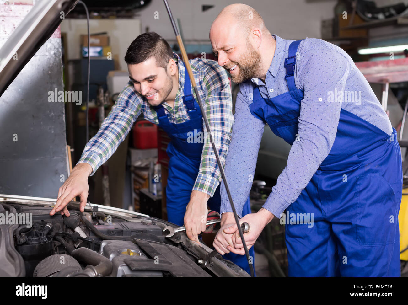 Portrait of two professional car mechanics working together at garage ...