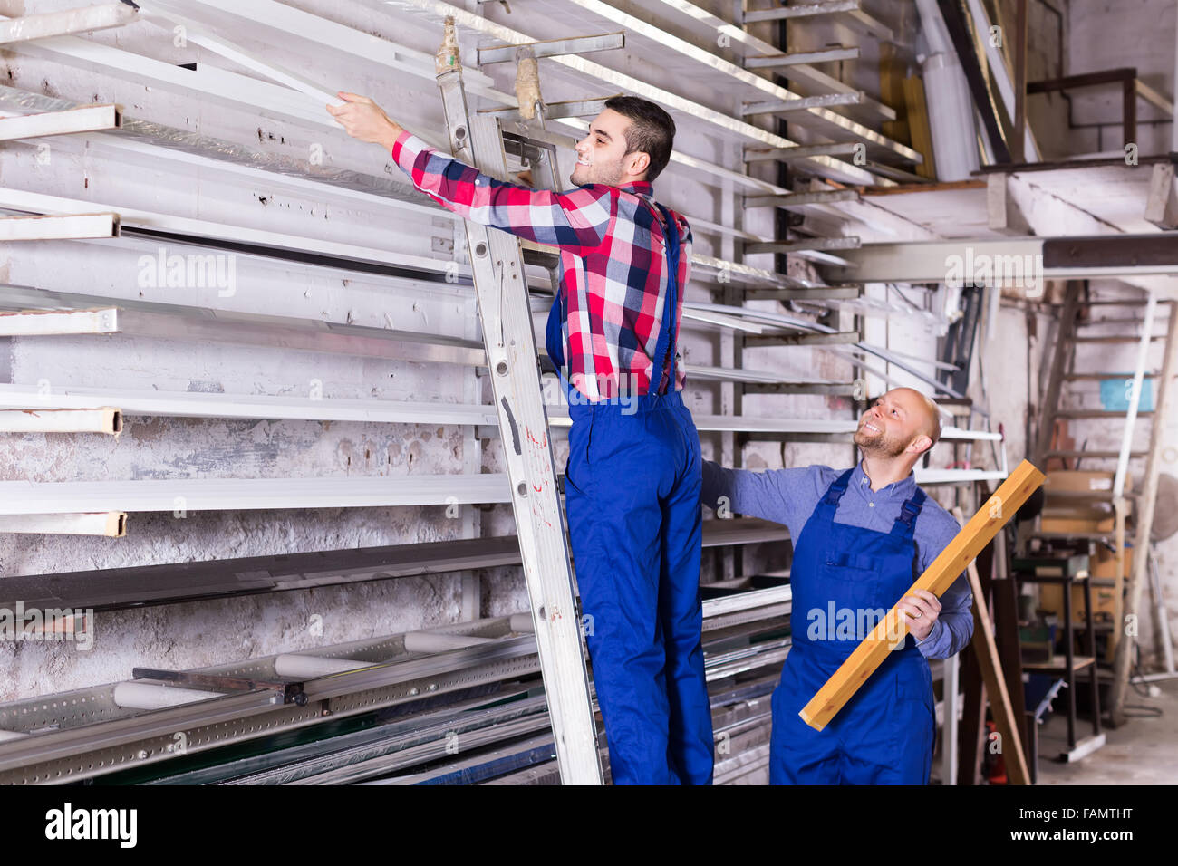 Two happy smiling workers in uniform choosing PVC window profile at ...