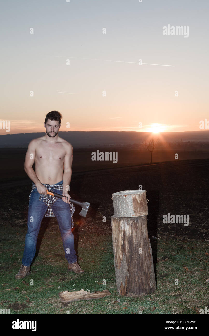 The stylish lumberjack chopping wood at sunset Stock Photo - Alamy