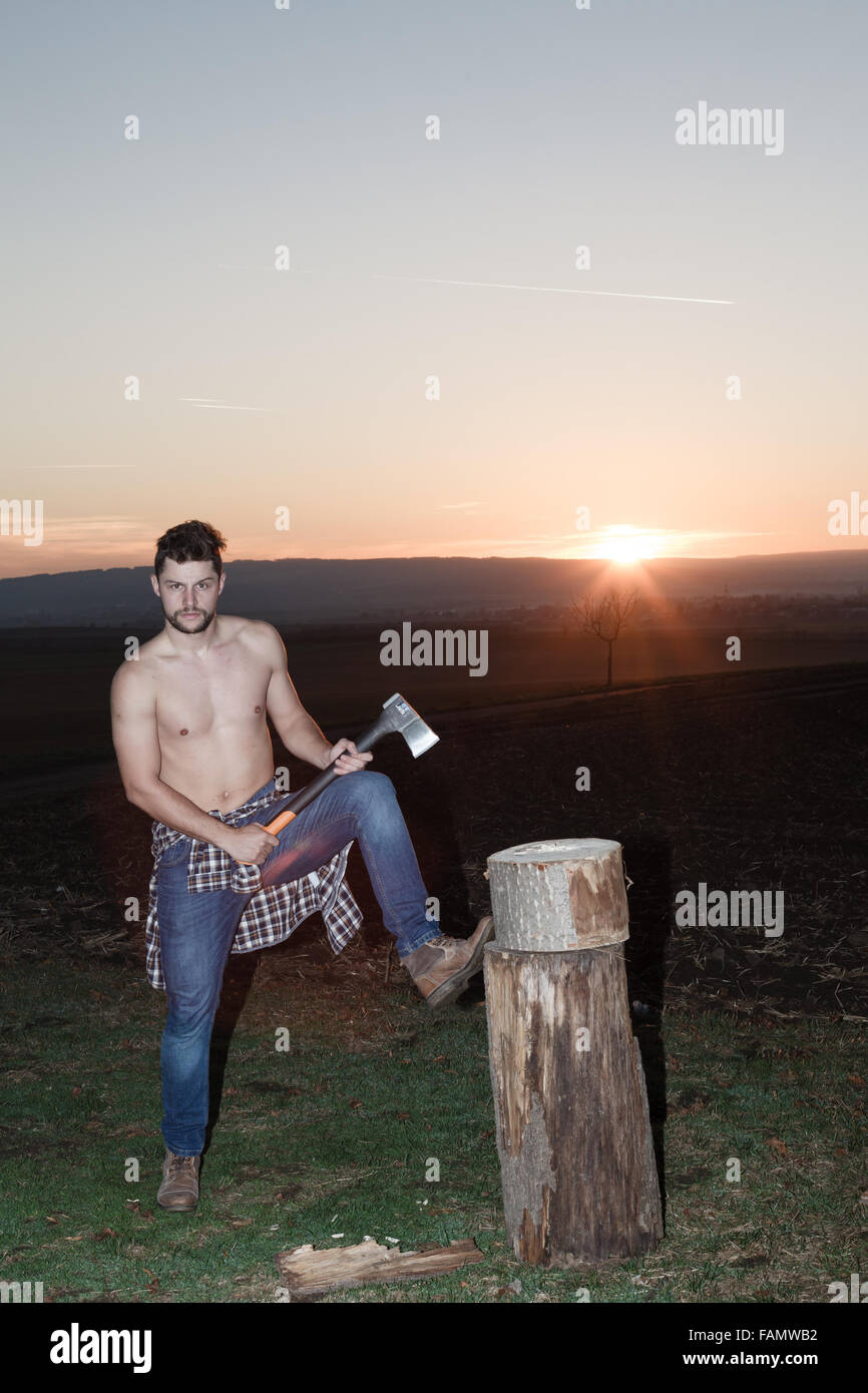 The stylish lumberjack chopping wood at sunset Stock Photo - Alamy