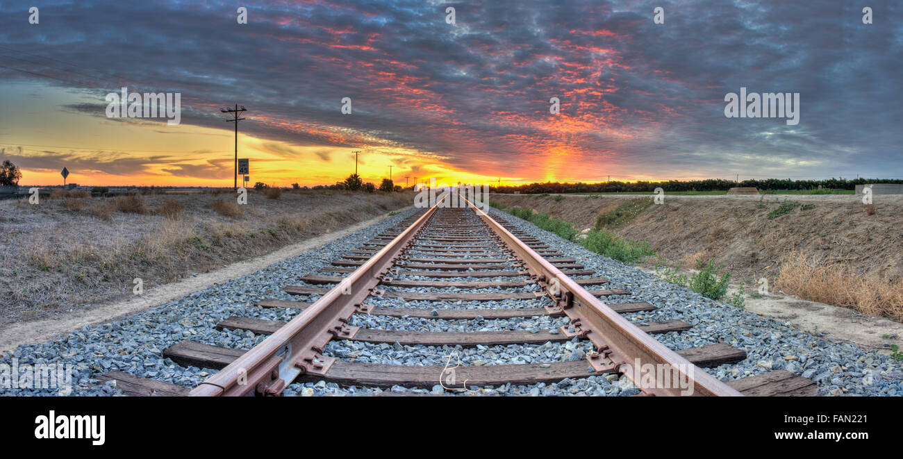 Panoramic view of train tracks leading into the sunset Stock Photo - Alamy
