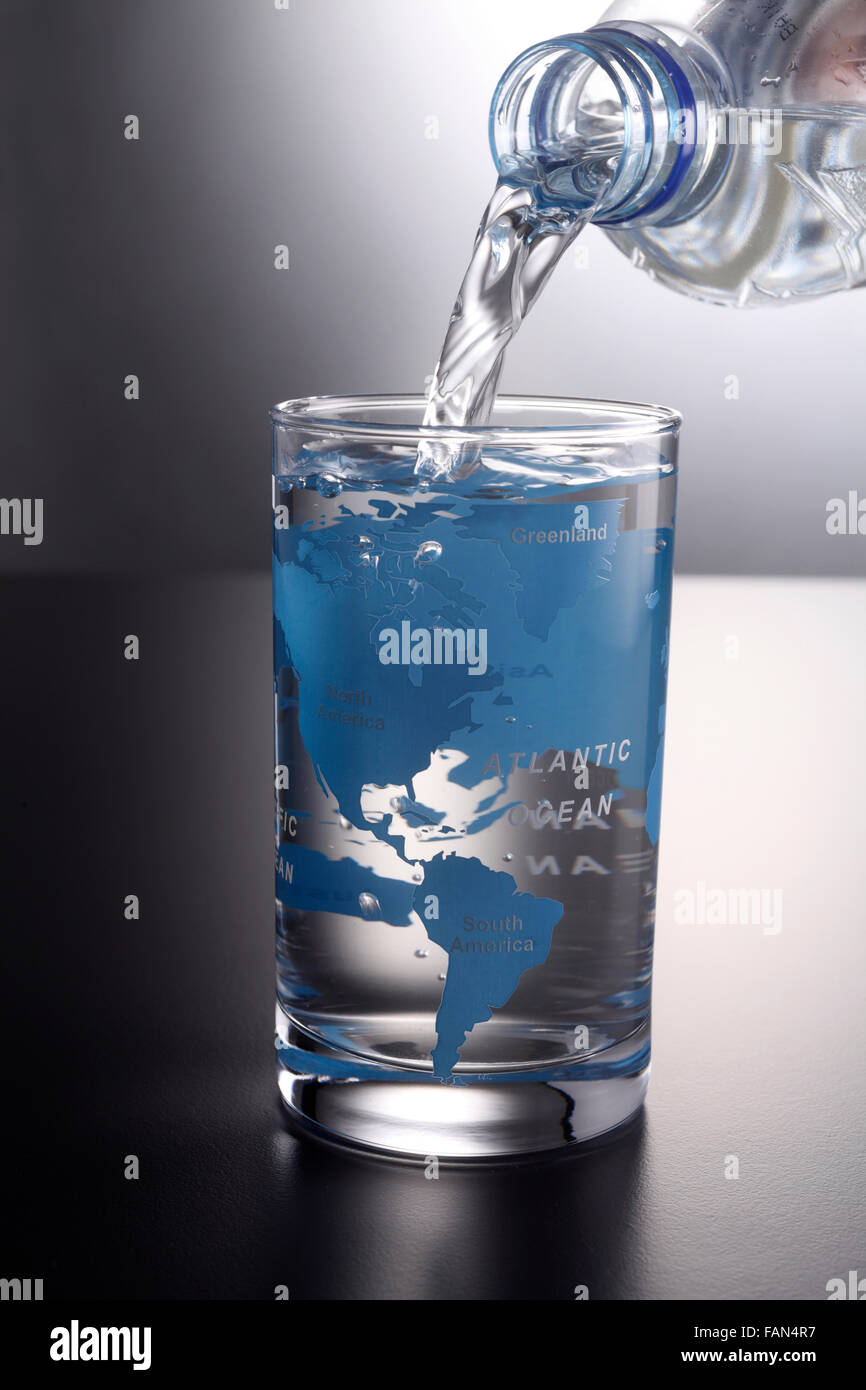 pouring water into a glass printed world map Stock Photo - Alamy