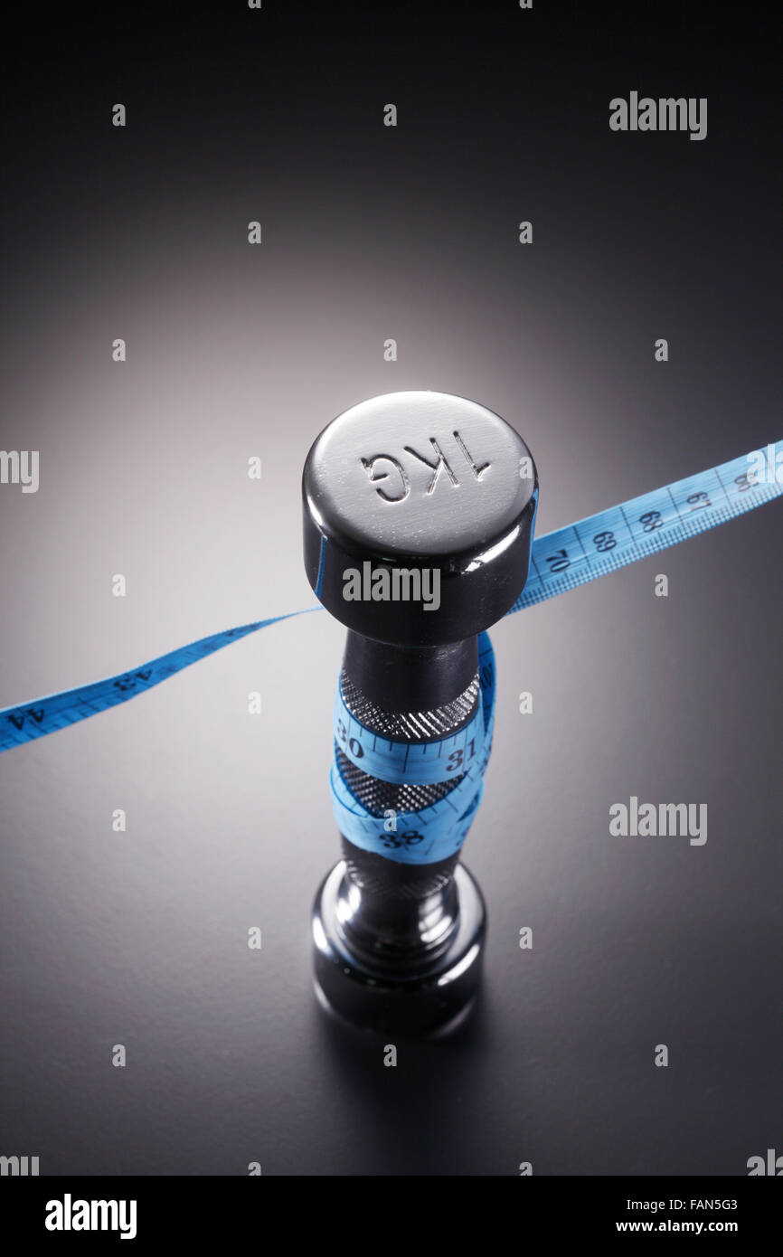 Measuring tape wrapped around dumbbell Stock Photo - Alamy