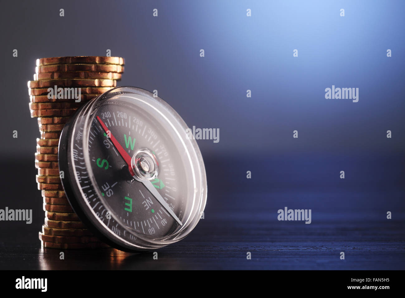 Stack of coins next to Compass Stock Photo - Alamy