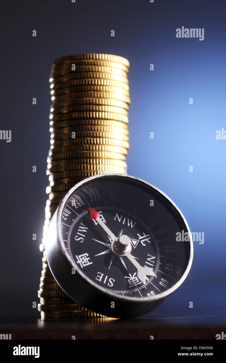 Stack of coins next to Compass Stock Photo - Alamy