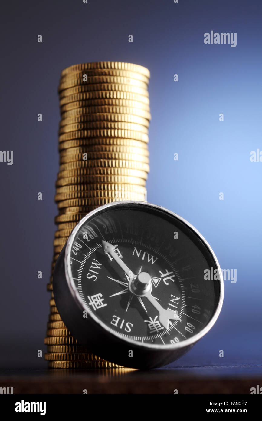 Stack of coins next to Compass Stock Photo - Alamy