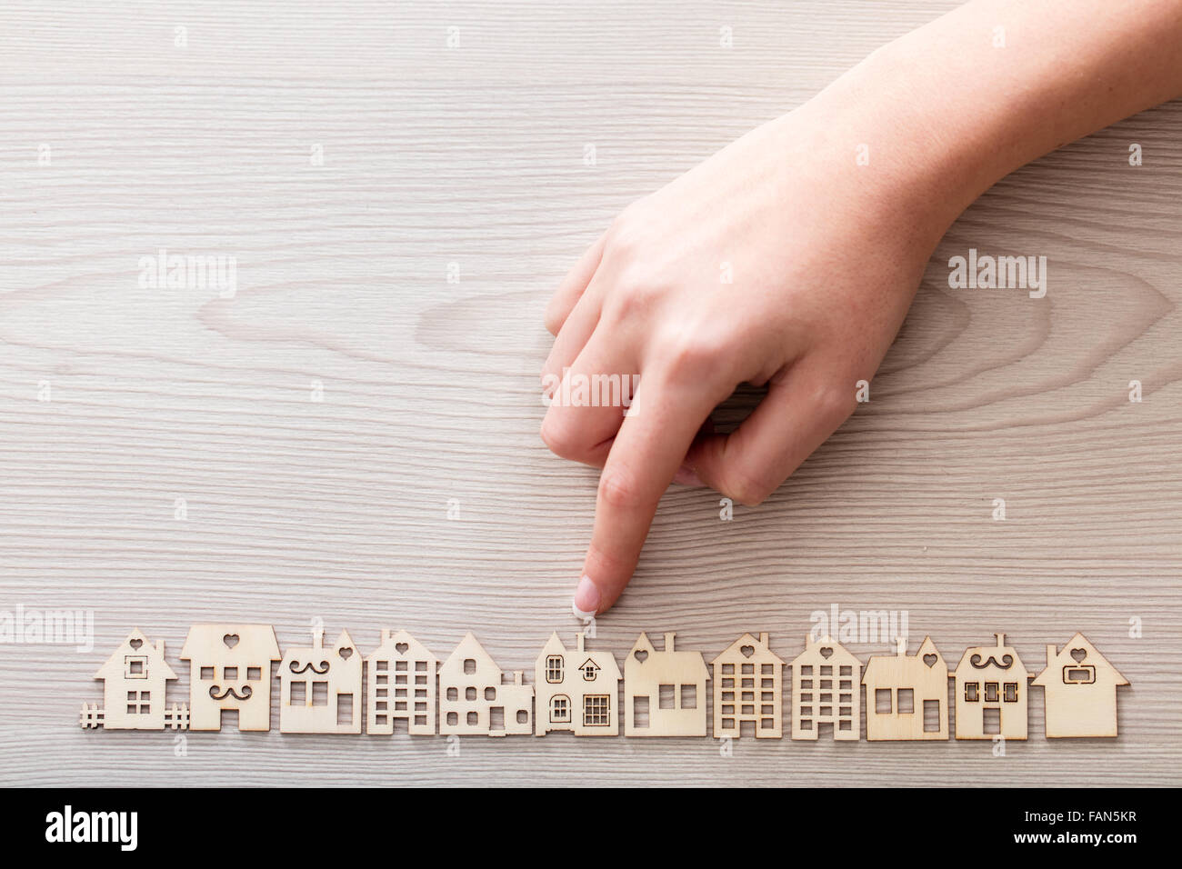 real hand pointing out a house model among the others mini figures in a ...