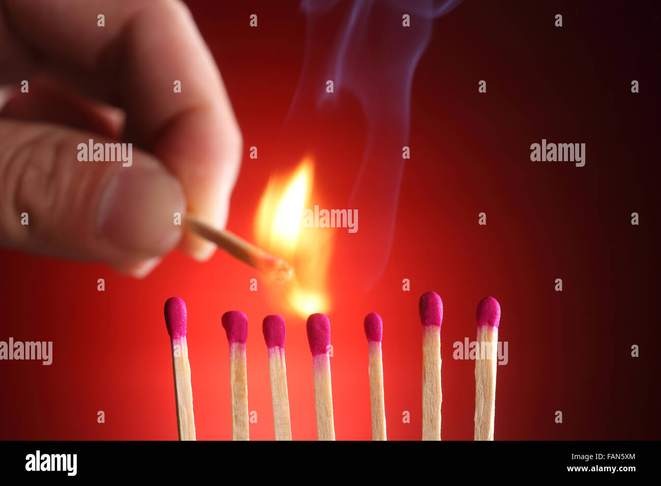 Light match near row of unlit matches Stock Photo - Alamy