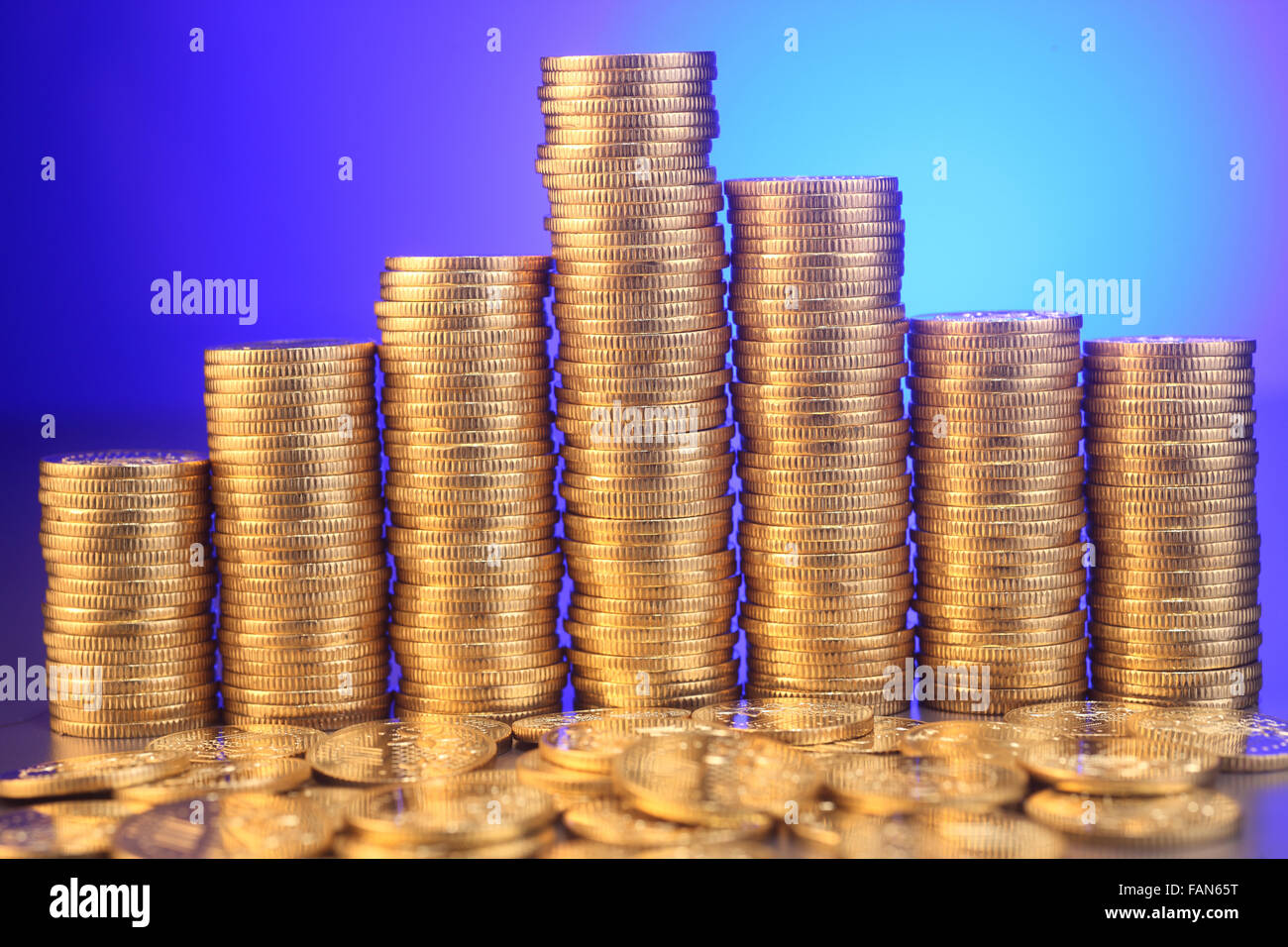 Piles of coins on the blue background Stock Photo - Alamy
