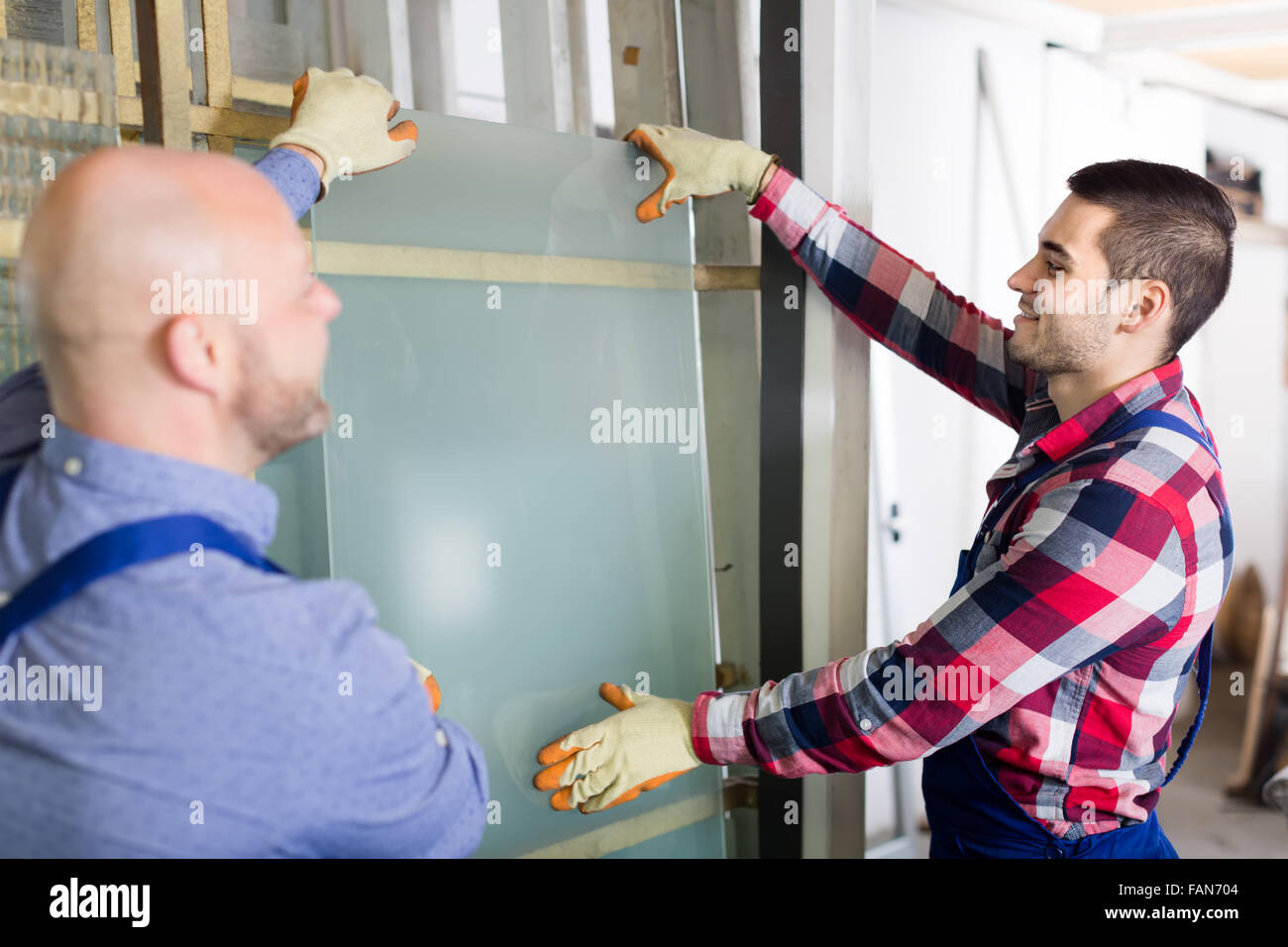 Two smiling production workers in coverall with different PVC window at ...
