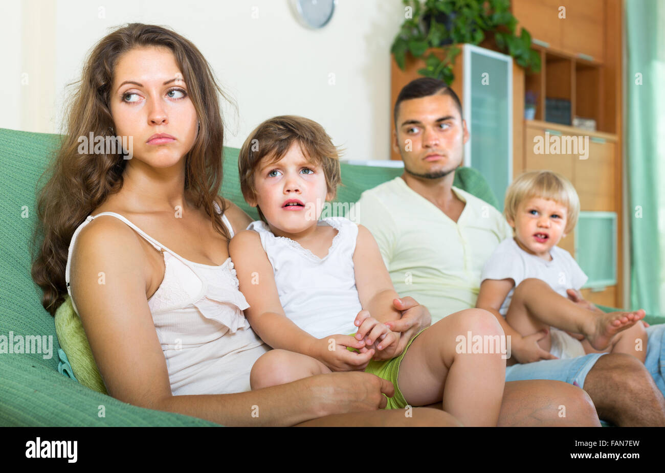 Depressed young parents with two little daughters after quarrel at home ...