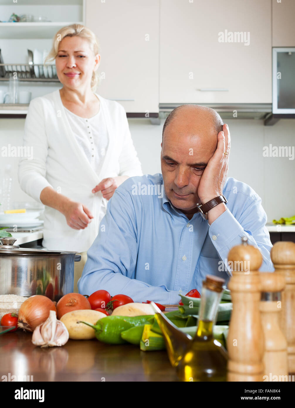 Sad man and mature woman during quarrel in kitchen at home Stock Photo ...