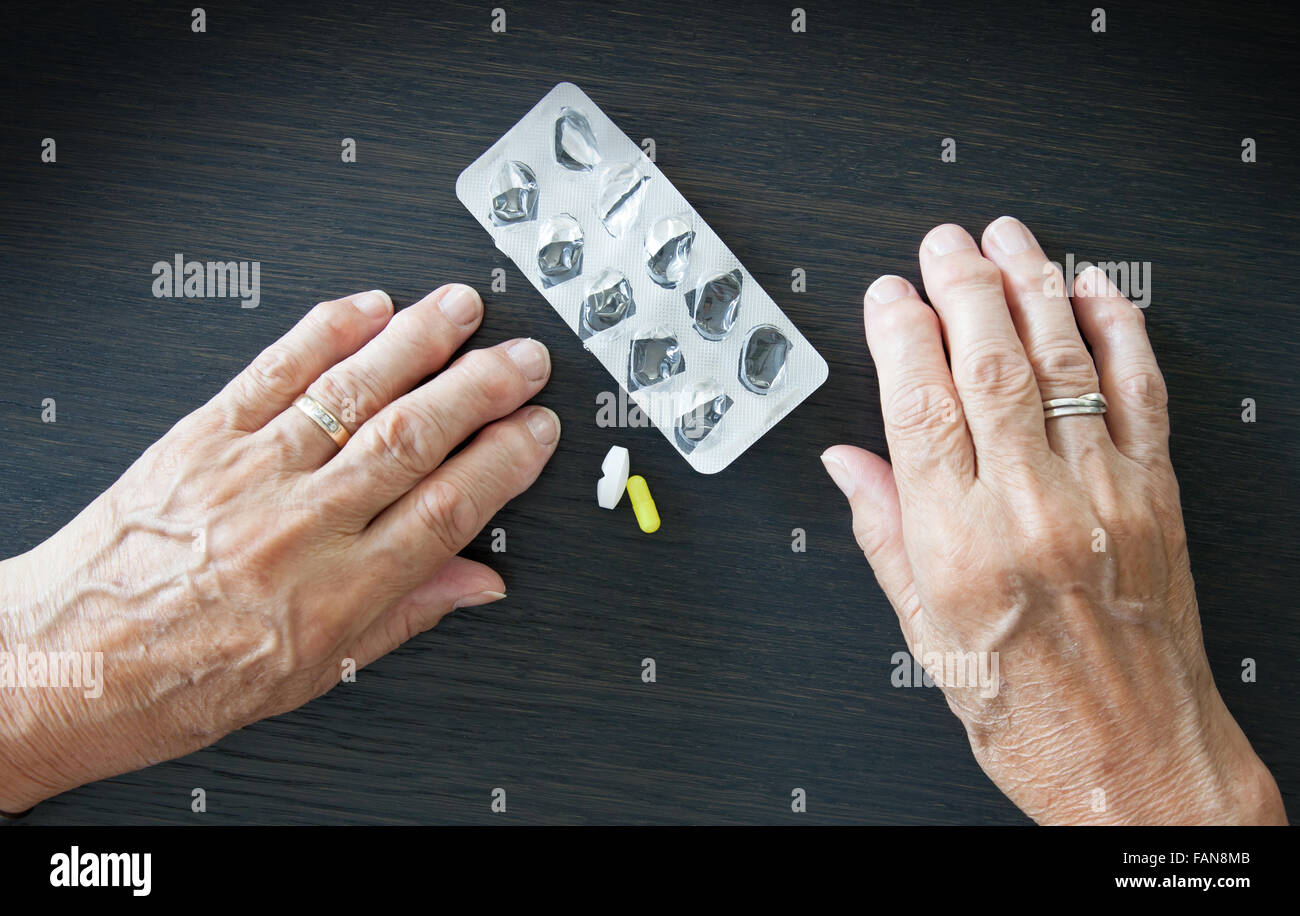 Elderly person taking medication, two different pills Stock Photo - Alamy