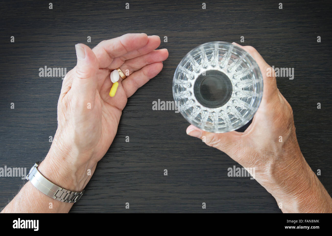Elderly person taking medication, two different pills Stock Photo - Alamy