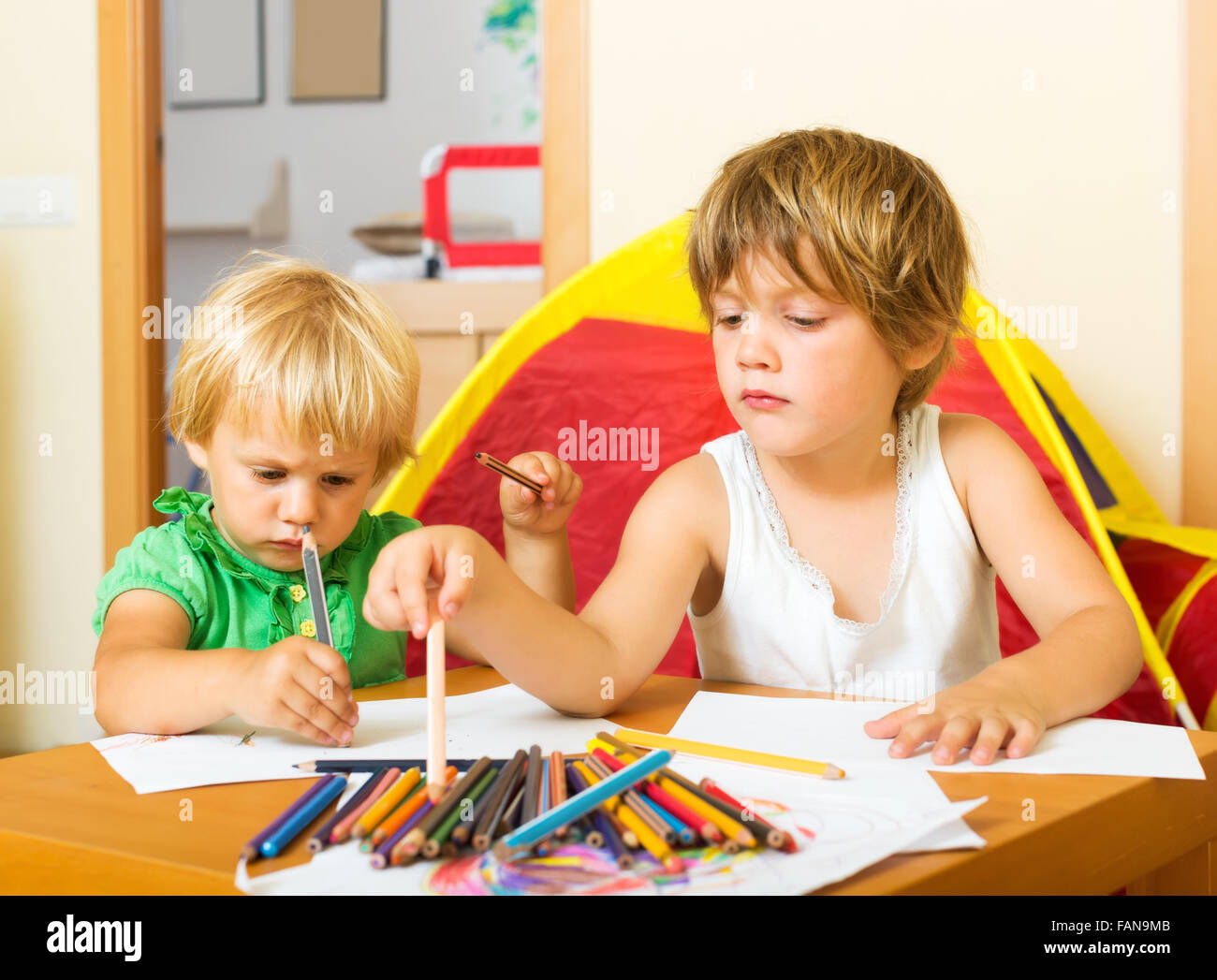 Two little children playing with pencils in home interior Stock Photo ...