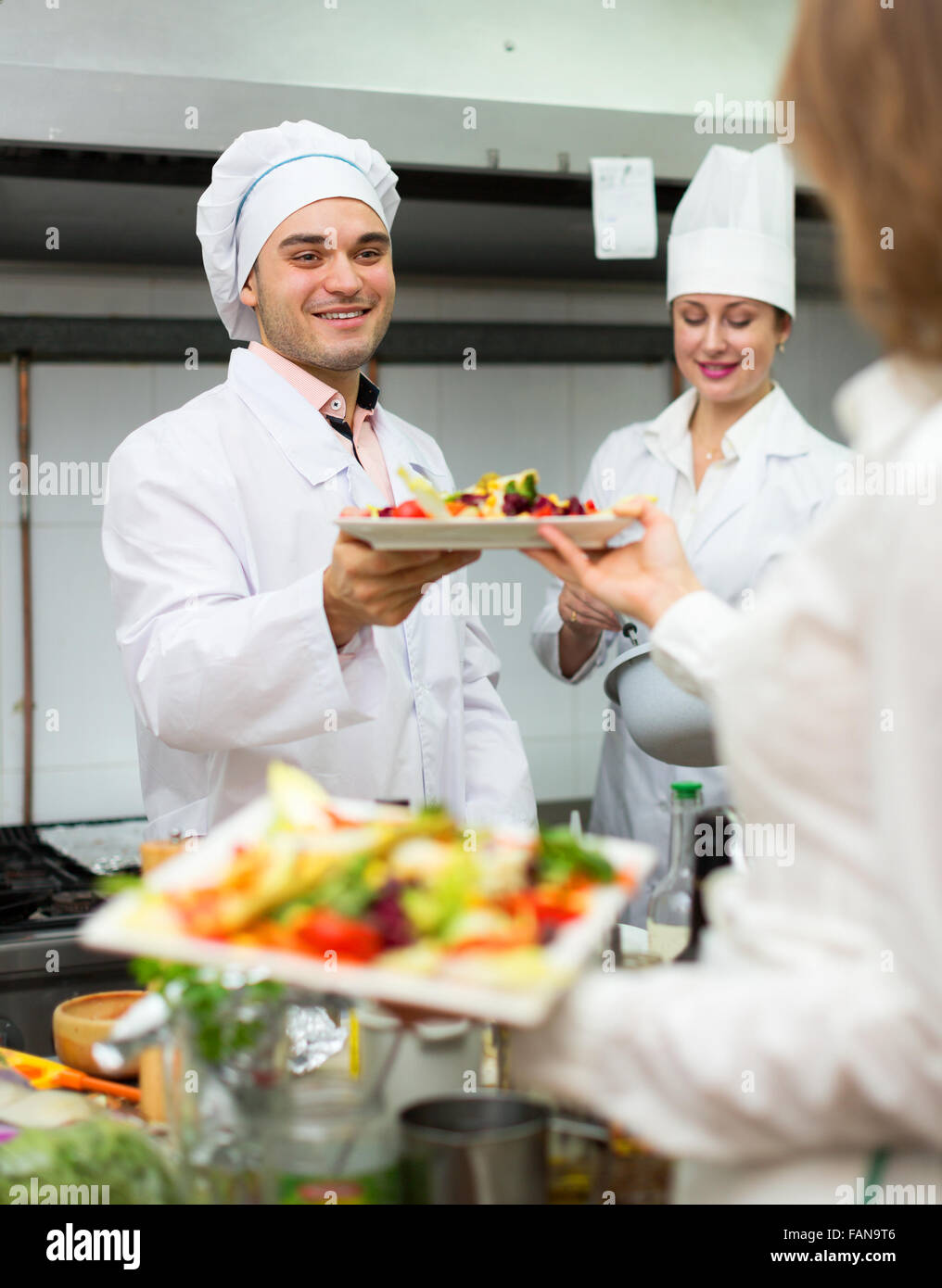 Team of chefs and young waiter at restaurant kitchen Stock Photo - Alamy