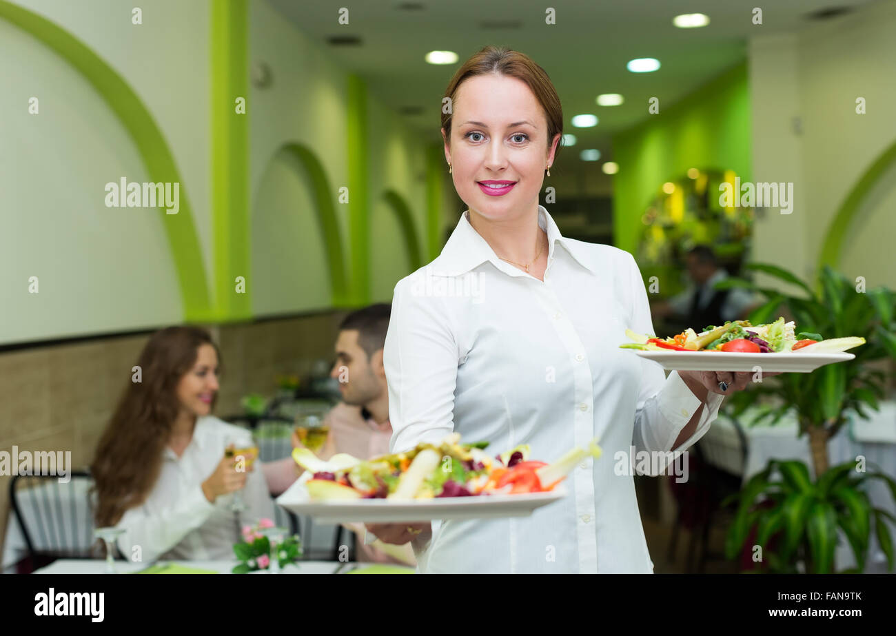 Clients at table and charming waitress with plates in cafe Stock Photo ...