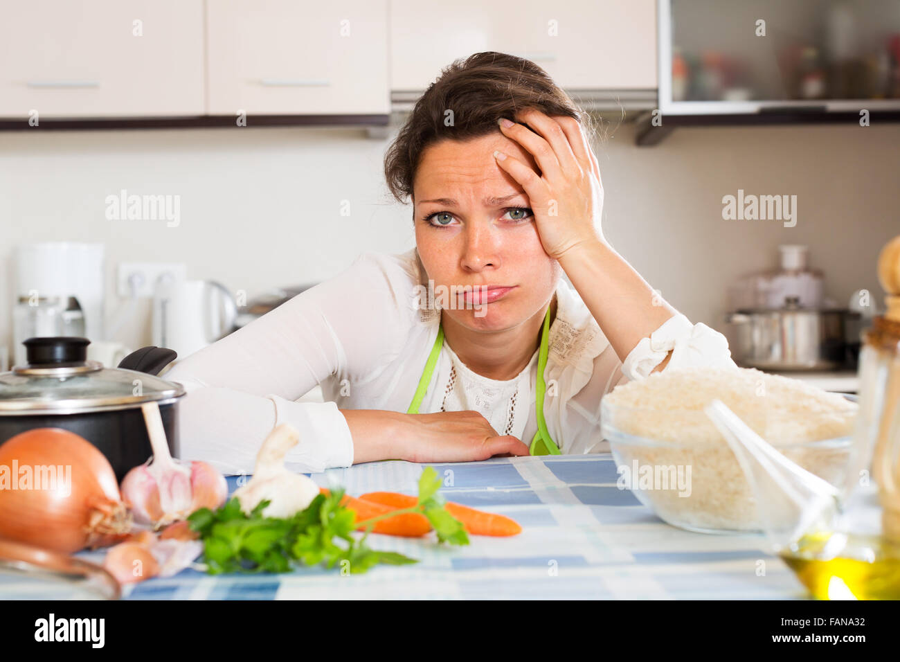 Sad housewife preparing rice with vegetables at home Stock Photo - Alamy