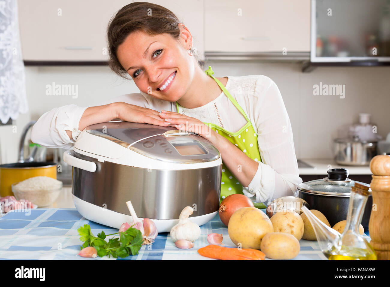 Happy smiling housewife cooking with new electric multicooker at home ...