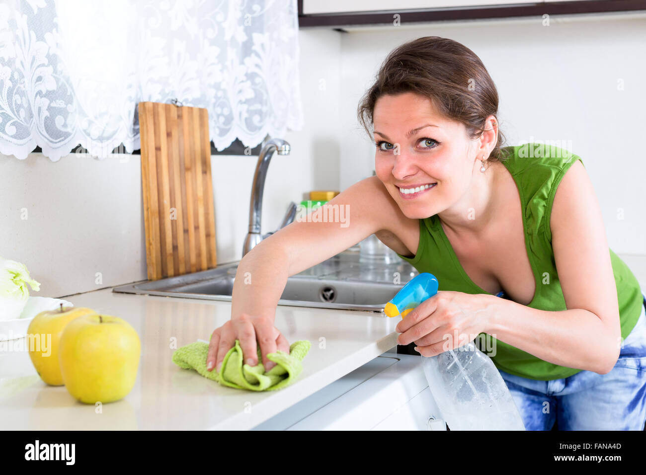 Woman with a rag and clear bottle with cleaning substance is cleaning ...