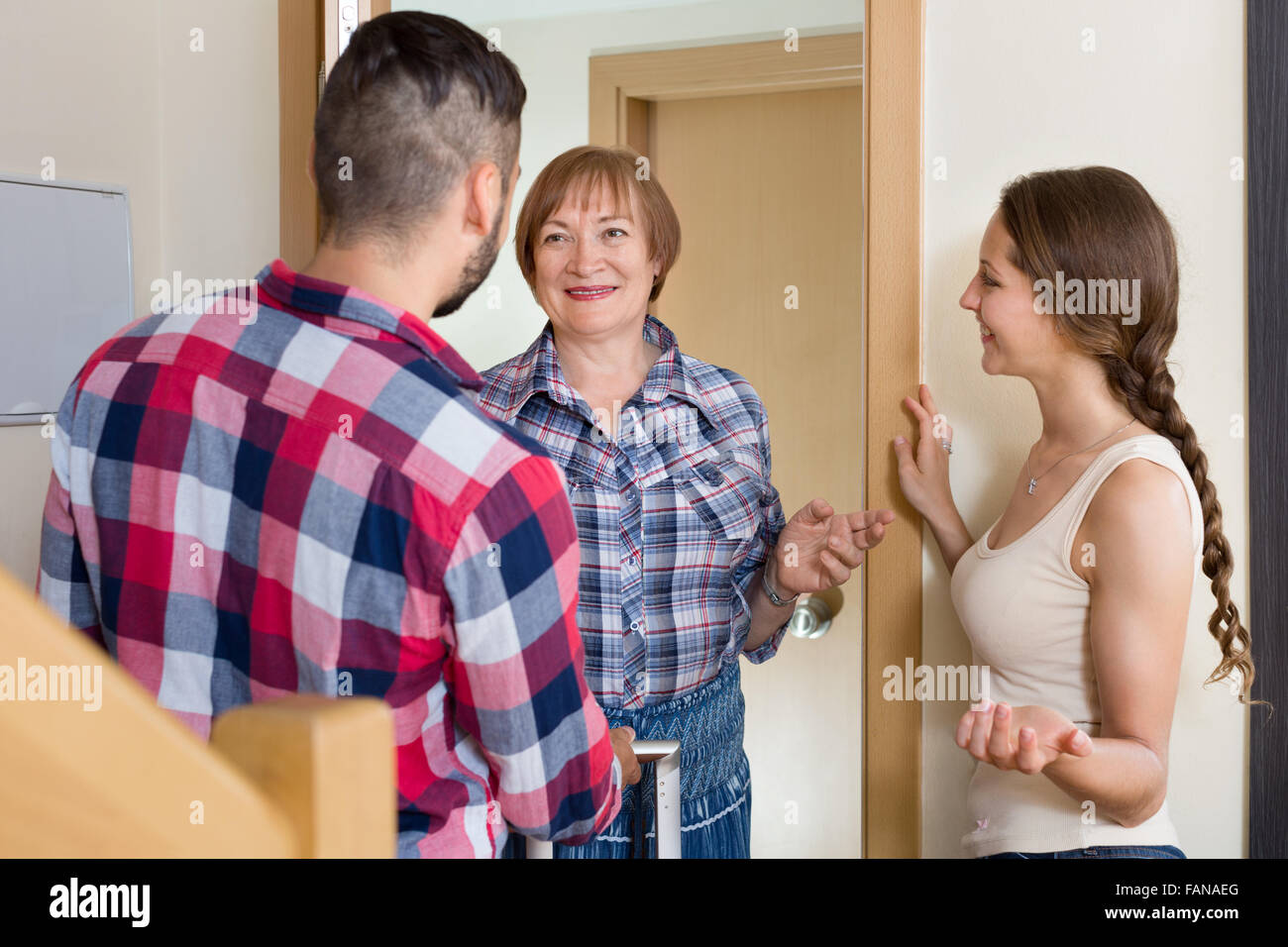 Happy mother greeting young beautiful couple at threshold Stock Photo ...