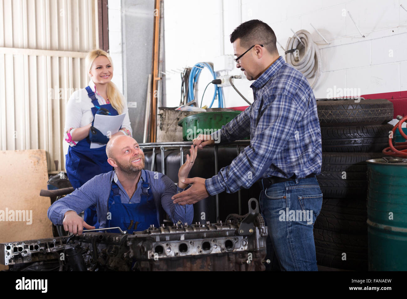 Posetive service crew and serious driver standing near car indoor ...